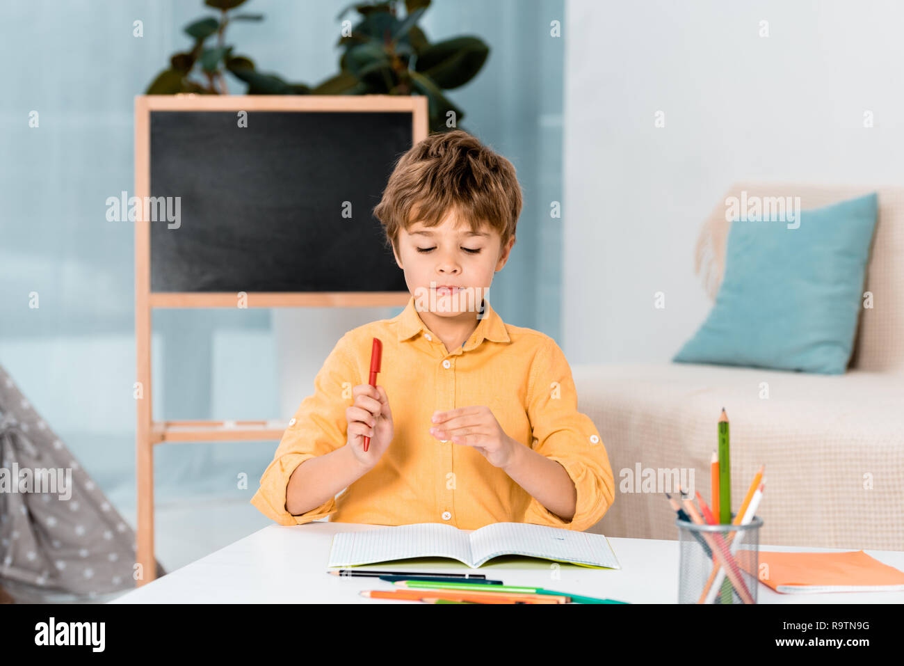 cute kid holding pen and studying at home Stock Photo - Alamy