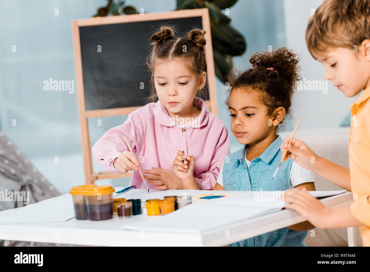 adorable little multiracial children painting together Stock Photo - Alamy
