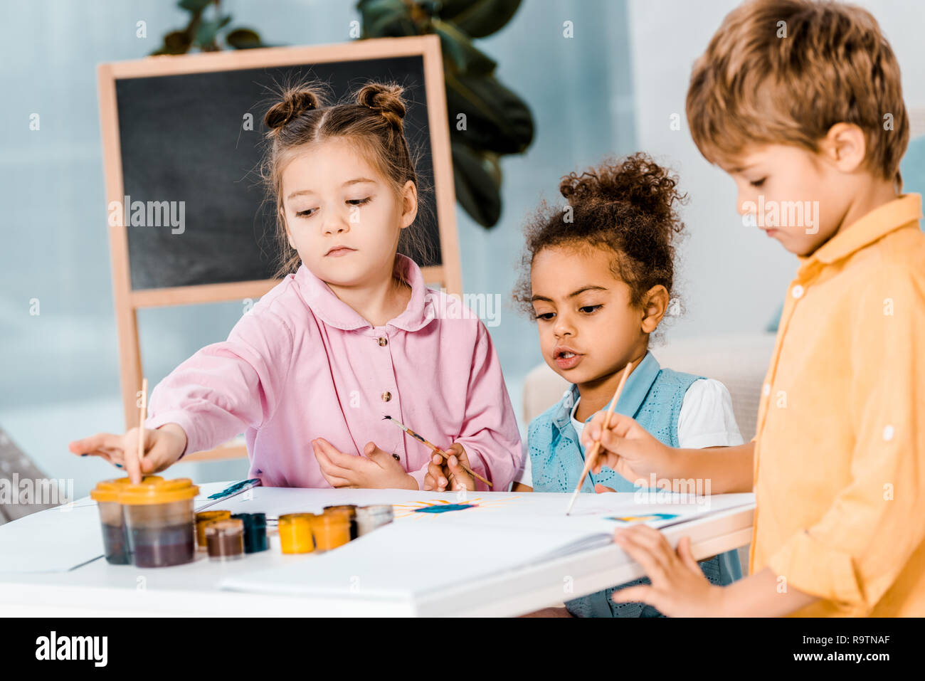 adorable multiracial children drawing with paints together Stock Photo ...