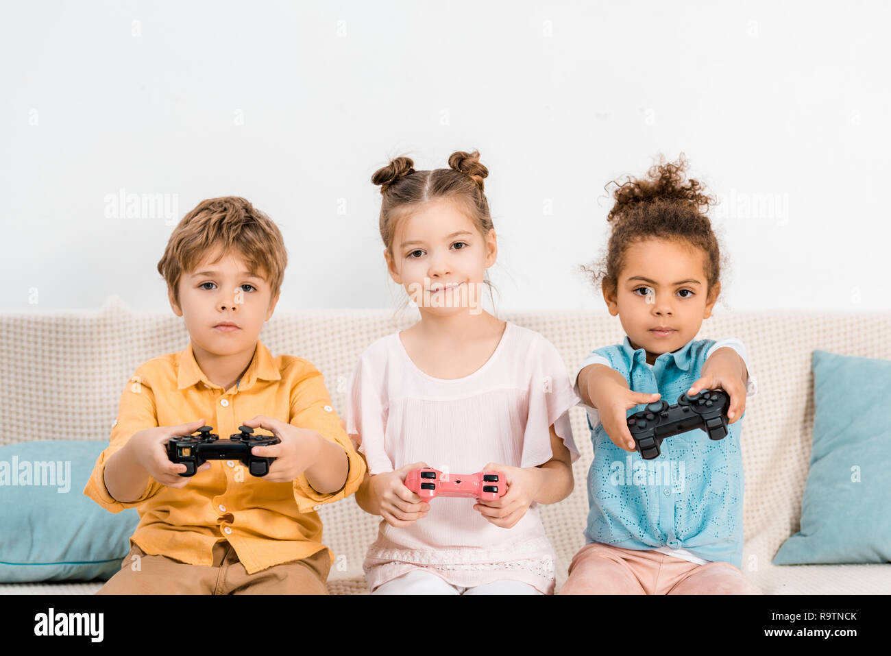 Cute little kids playing video game with joysticks and looking at ...