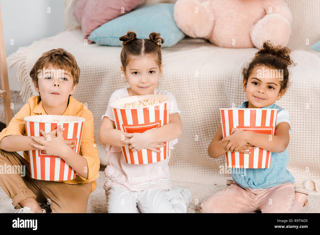 adorable little kids holding boxes with popcorn and smiling at camera ...