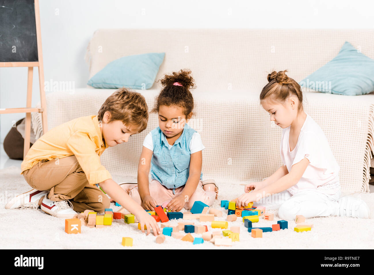 cute little children playing with colorful cubes on carpet Stock Photo ...