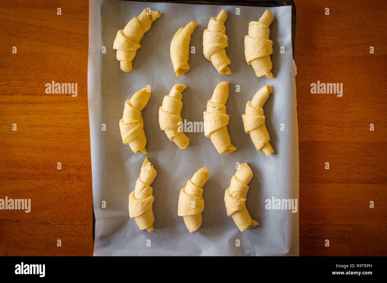 Raw croissant roll dough on parchment paper and pan ready for the oven ...