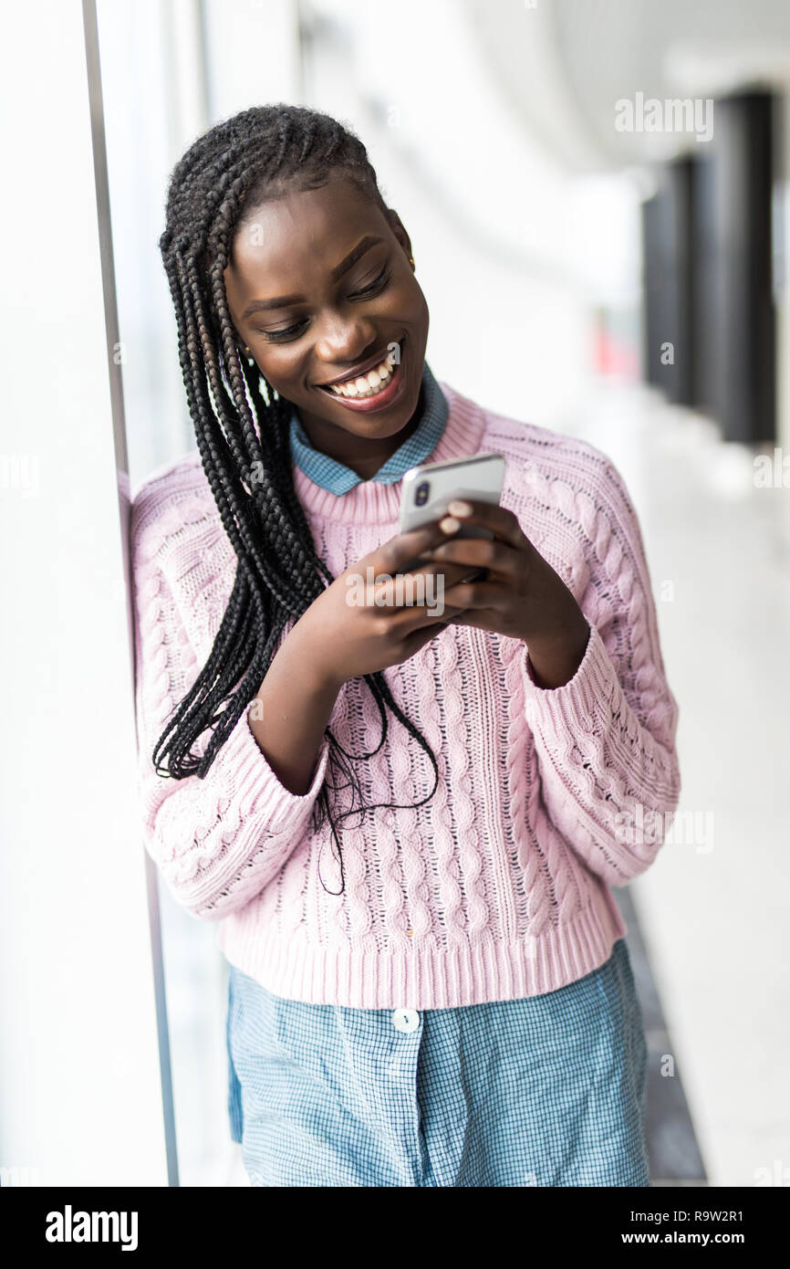 Young african woman surf in internet in mobile phone in front of panoramic windows Stock Photo ...