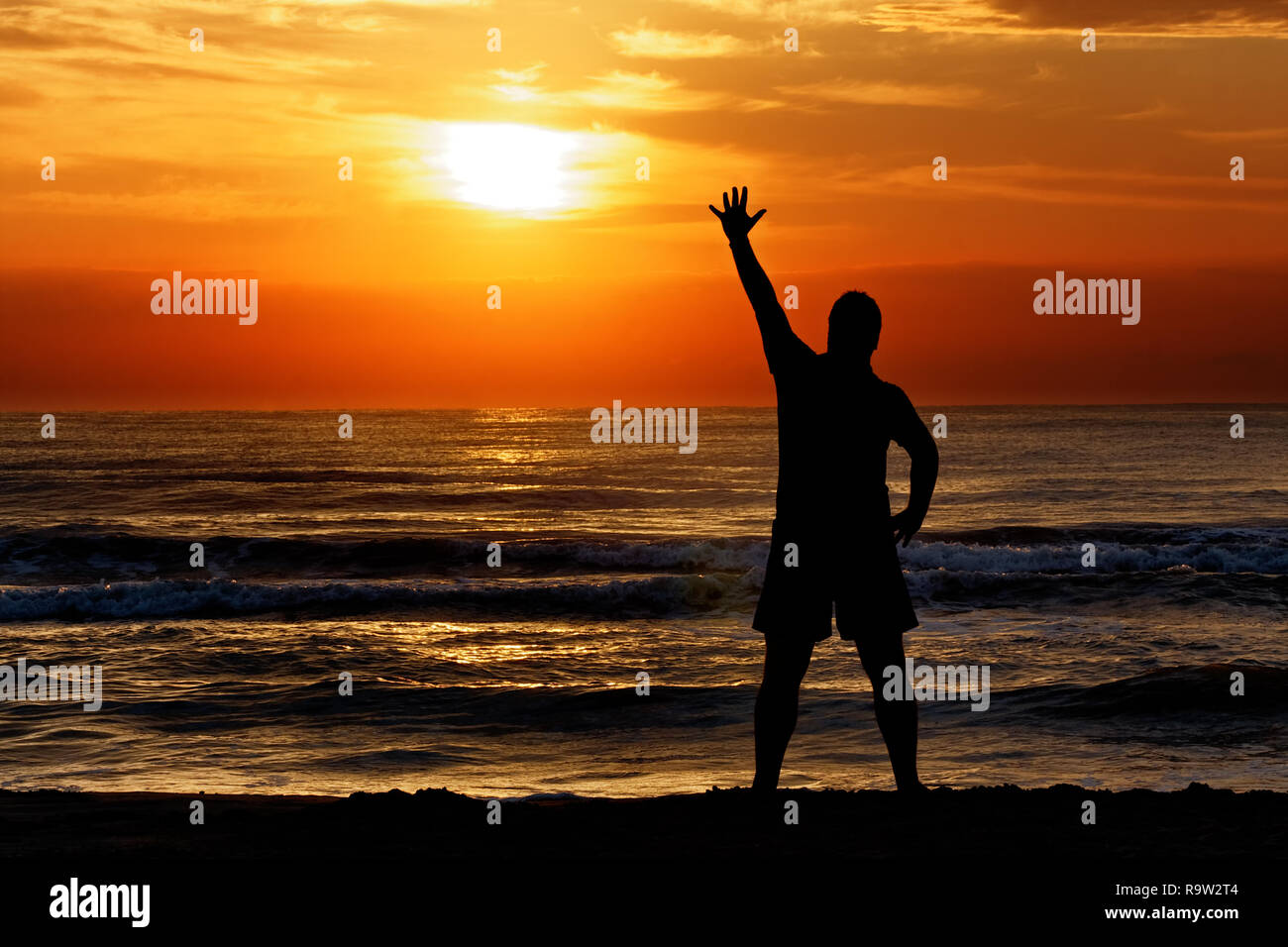 Man silhouette waving sun at sunset at sea on the beach Stock Photo - Alamy