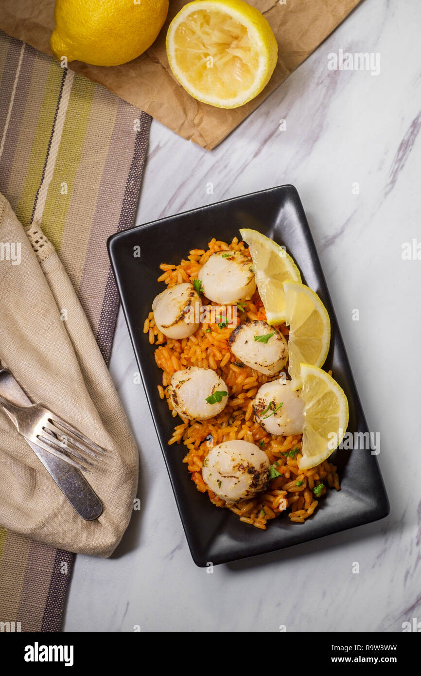 Orange Spanish rice paella with lemon herb scallops Stock Photo - Alamy