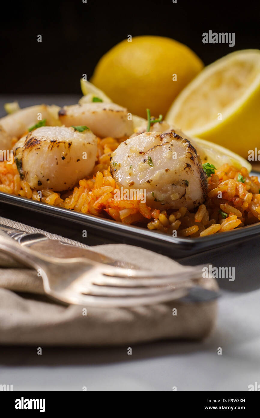 Orange Spanish rice paella with lemon herb scallops Stock Photo - Alamy