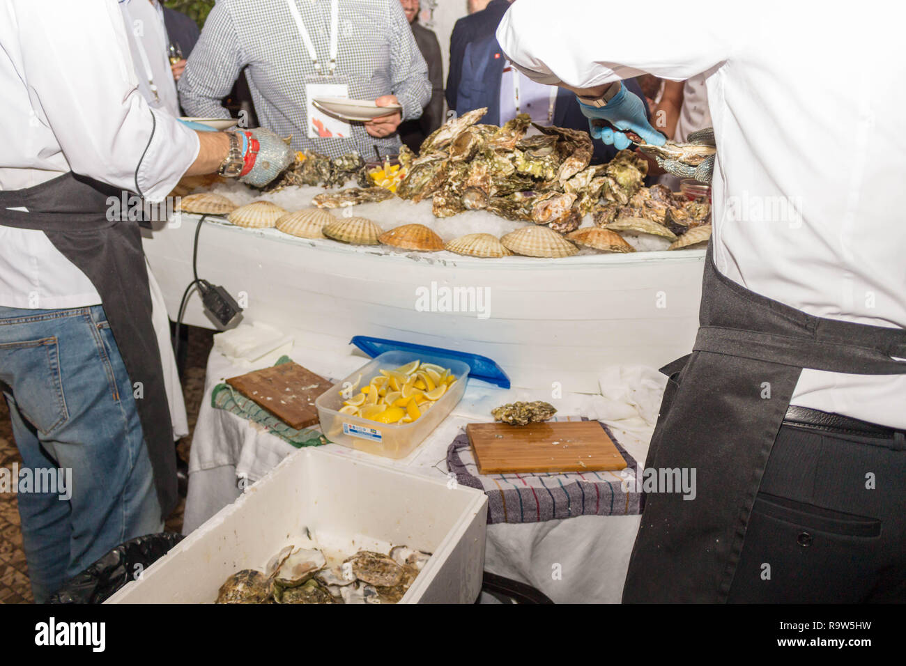 Two people clean oysters from shells for all visitors Stock Photo - Alamy