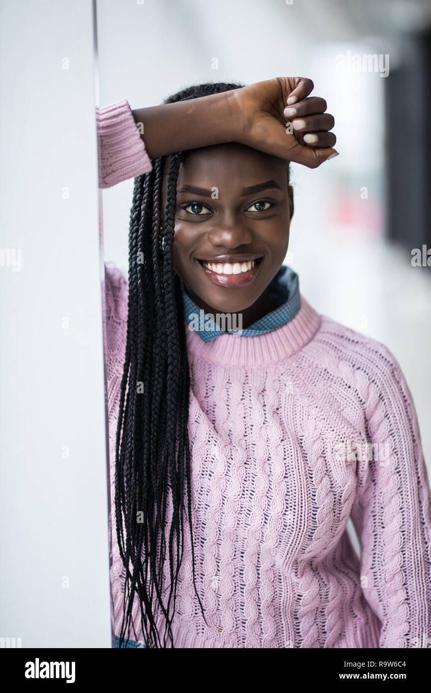 Young relaxed afro american woman smile standing on panoramic windows ...