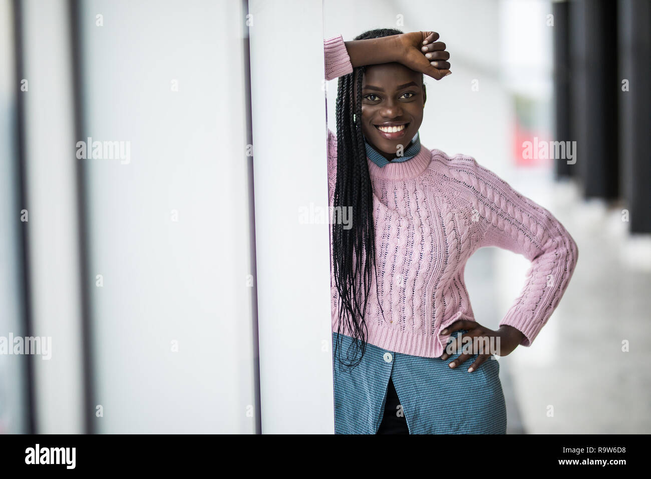 Young relaxed afro american woman smile standing on panoramic windows ...