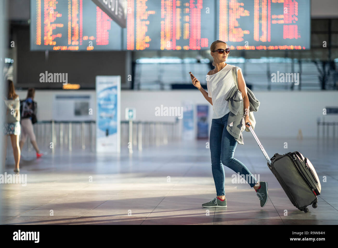 Young woman with her luggage at an international airport, before going ...