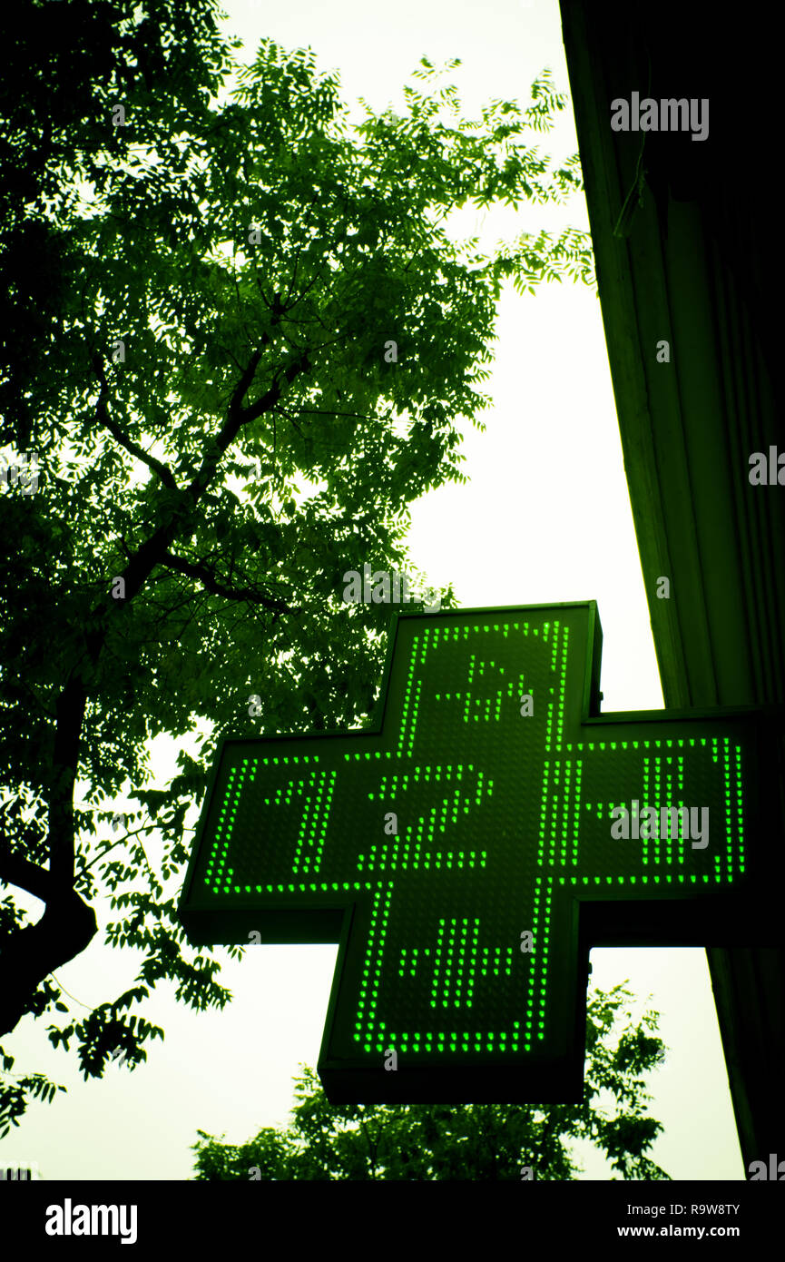 Pharmacy sign indicating open twelve hours. Green cross Stock Photo - Alamy