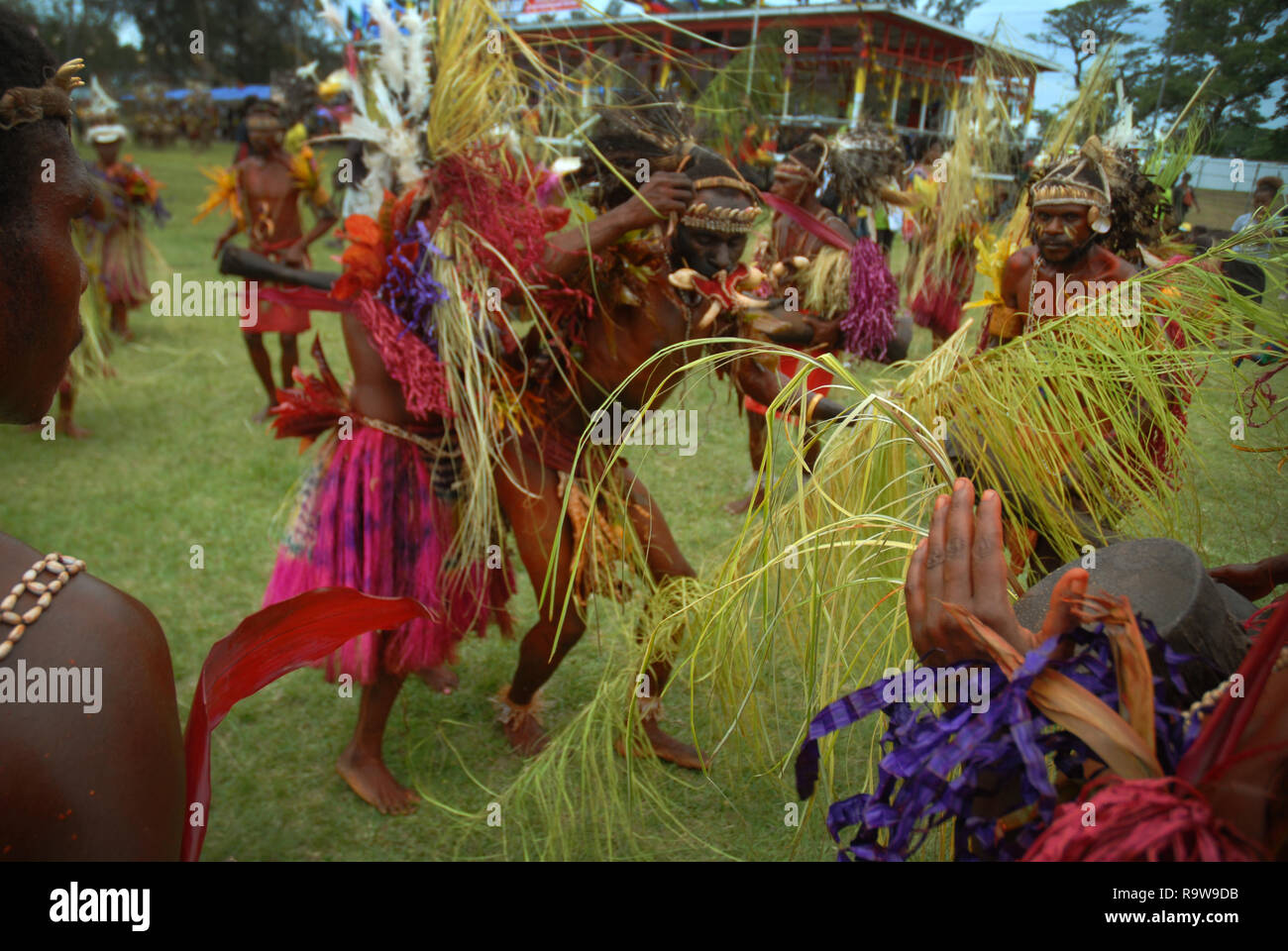 Colourfully dressed and face painted men and women dancing as part of a ...
