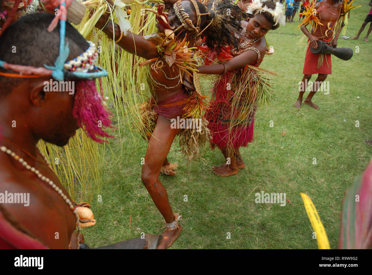 Colourfully dressed and face painted men and women dancing as part of a ...