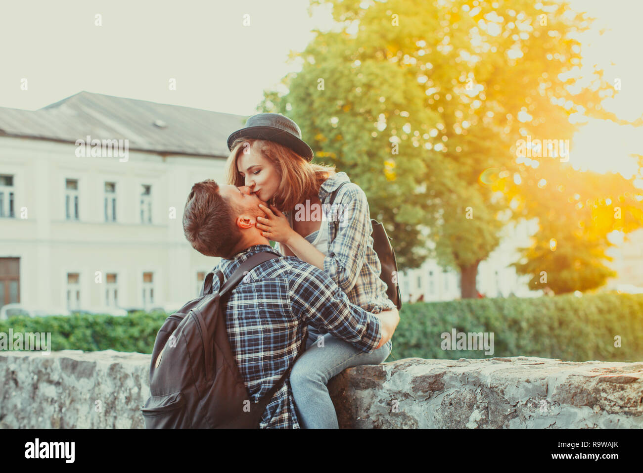 Emotional pair kissing sitting on the old stone wall Stock Photo - Alamy
