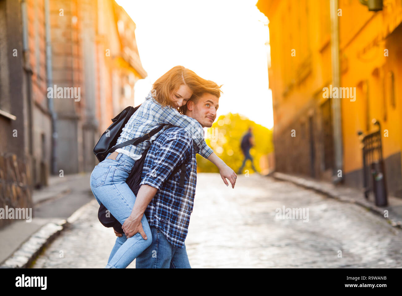 Man carrying woman on his back, old city background Stock Photo - Alamy
