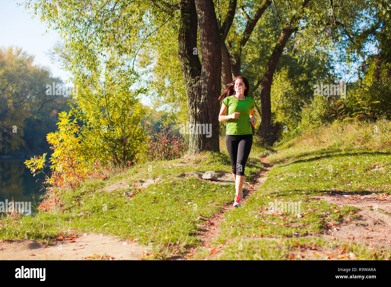 Young fit sport model running through the forest Stock Photo - Alamy