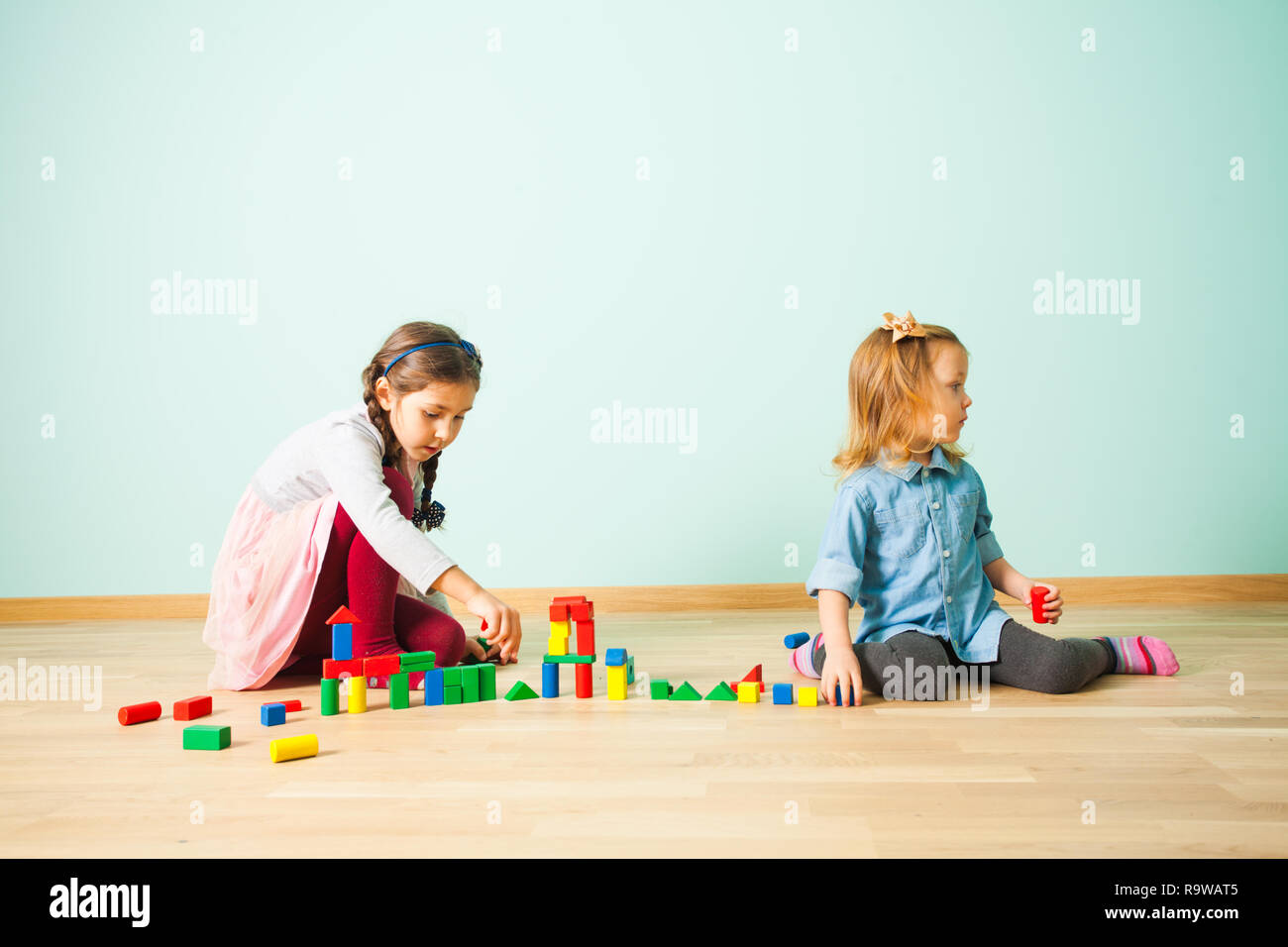 Two little girls building with blocks at home Stock Photo - Alamy