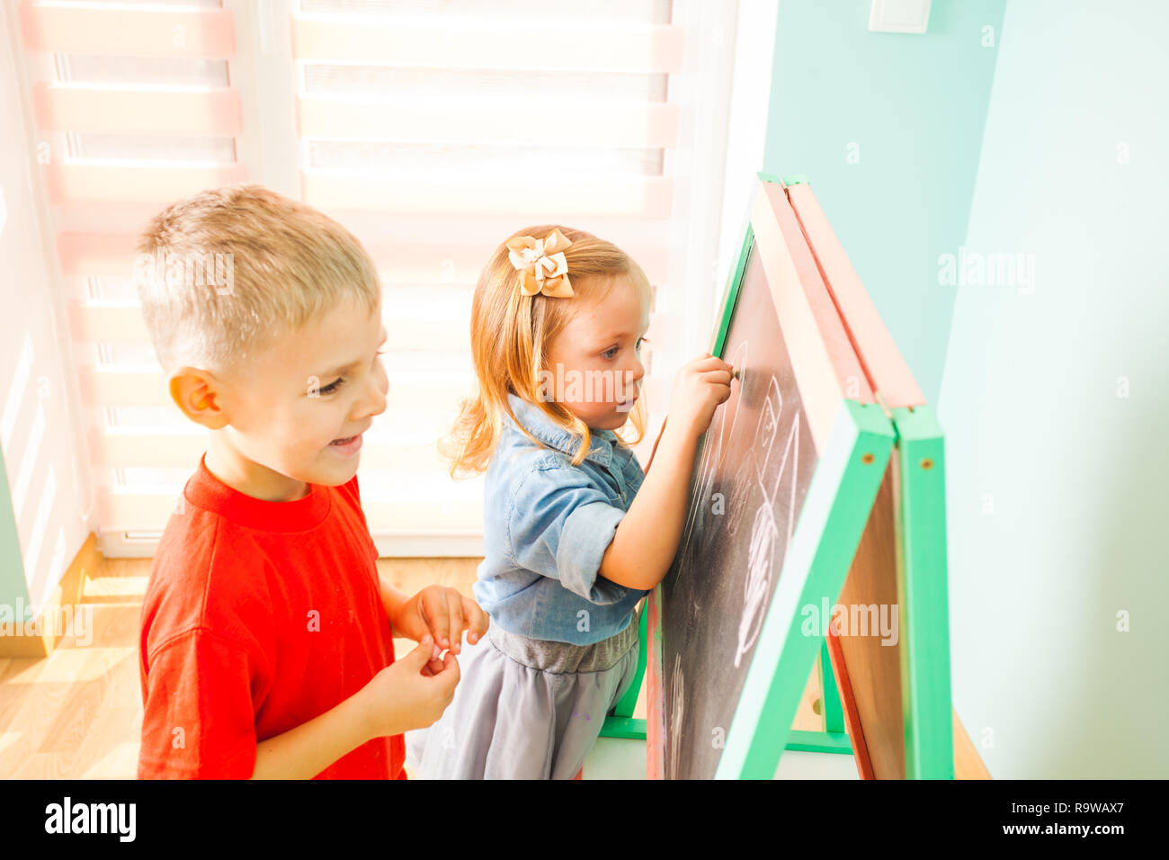 Happy kids writing on a blackboard at the kindergarten Stock Photo - Alamy