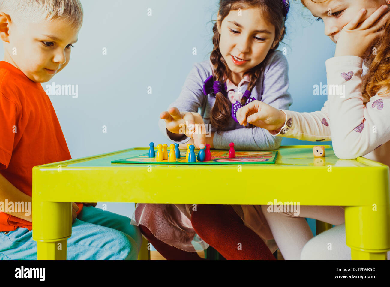 Close view of children faces around table with board game Stock Photo ...