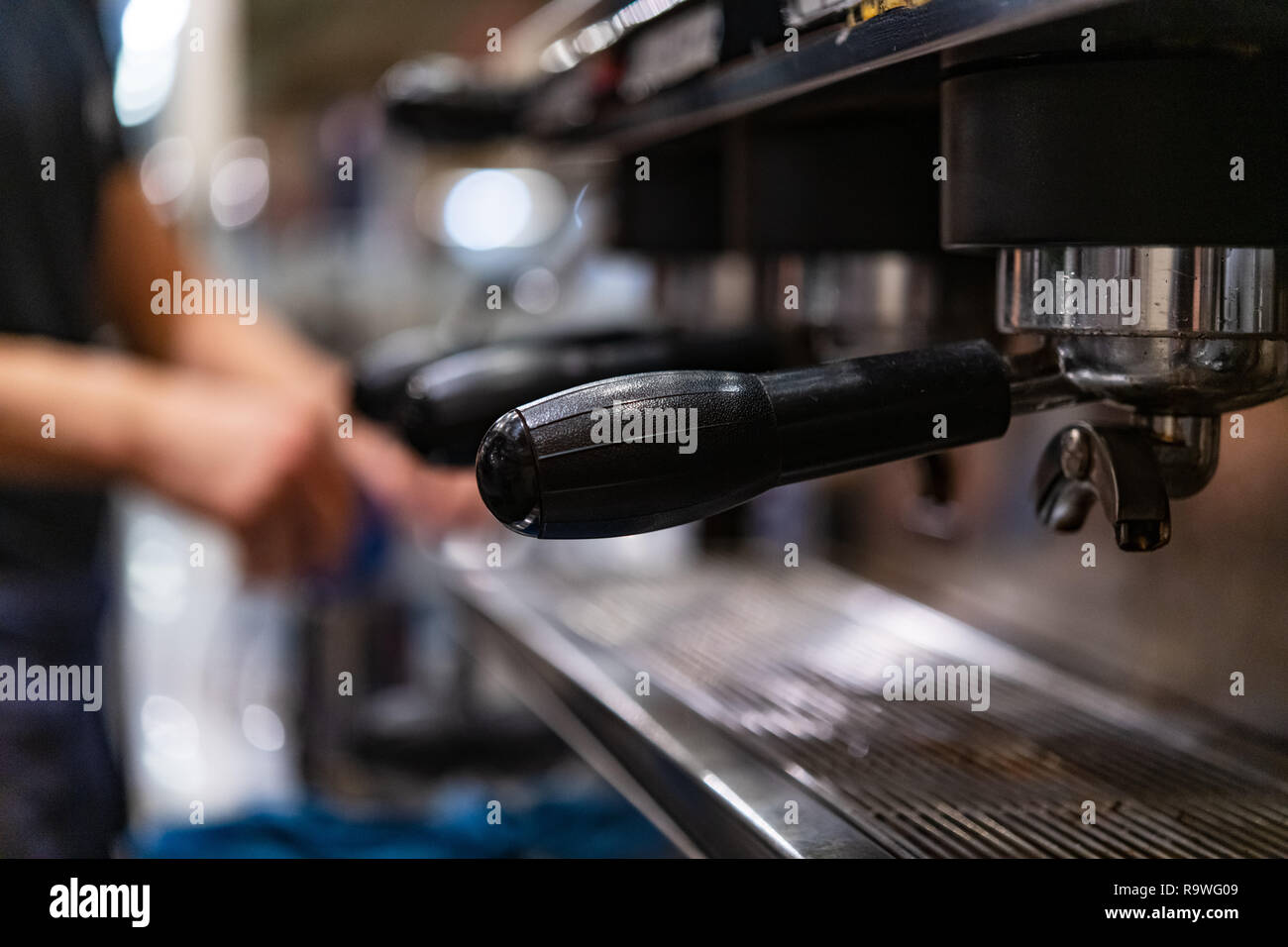 Detail of black espresso coffee machine in a bar, bartender human hands ...