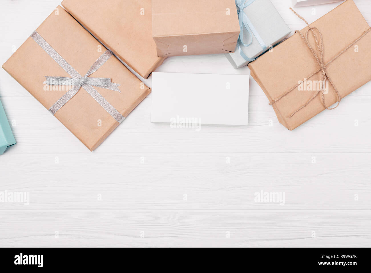 Pile of gifts on white wooden table, view from above with copy space ...