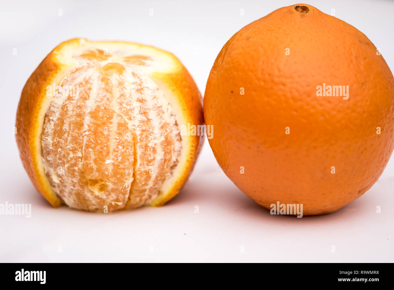 The one peeled orange and one unpeeled on the white background for eating Stock Photo - Alamy