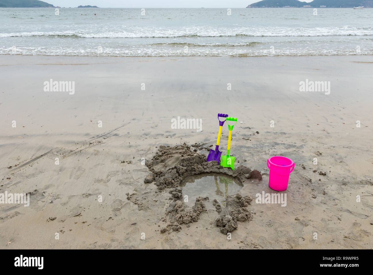 toy shovels and bucket with a hole on a beach Stock Photo - Alamy