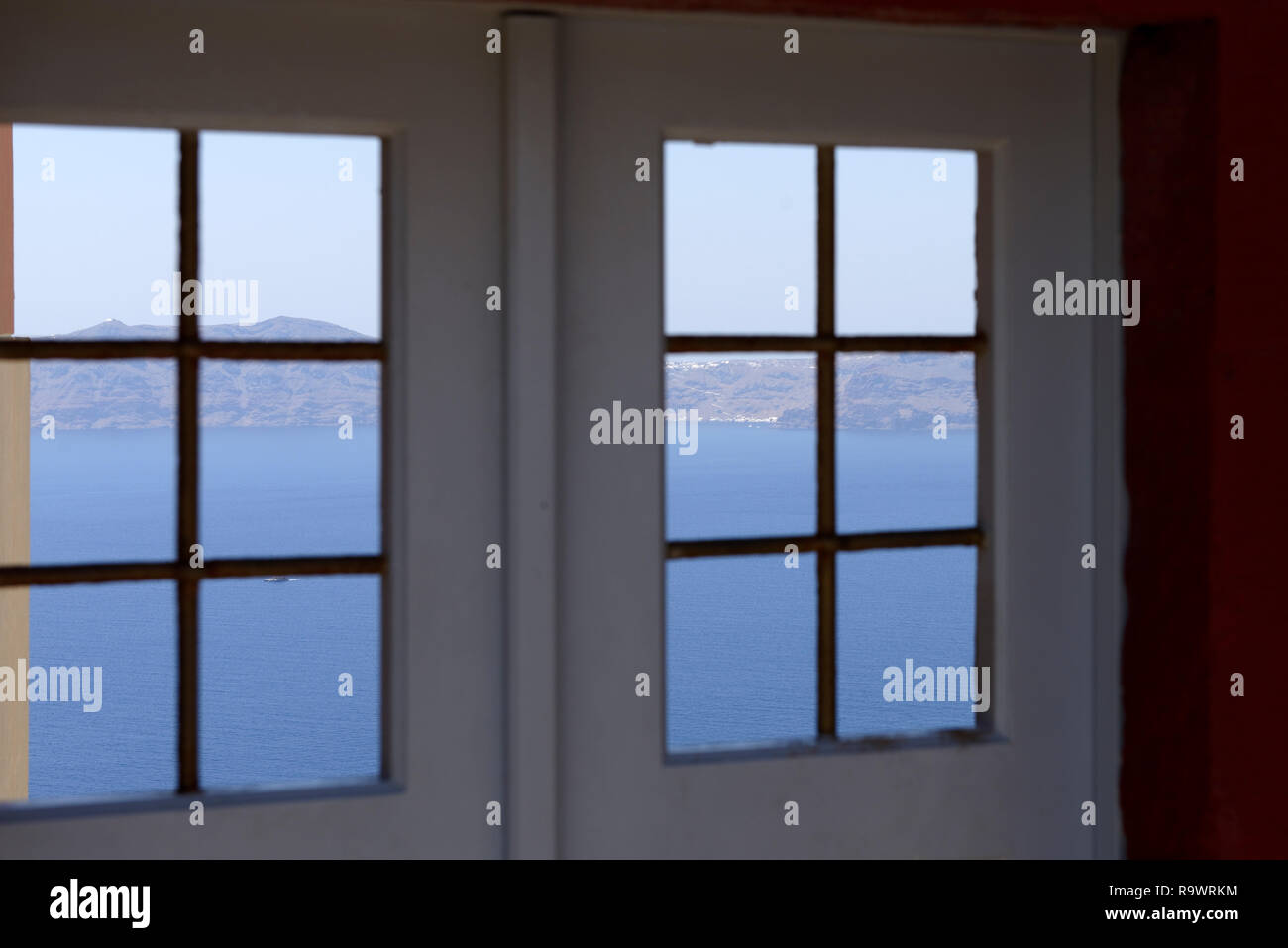 Door with a window view of the blue waters of the Caldera, Fira ...