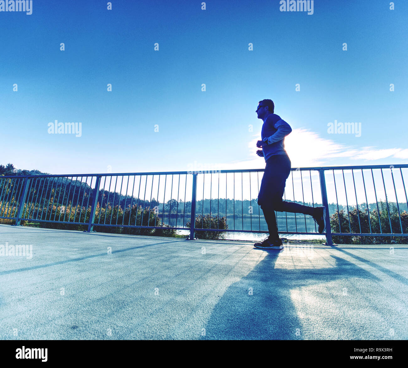 Tall slim man run on the lake terrace against the backdrop of a ...