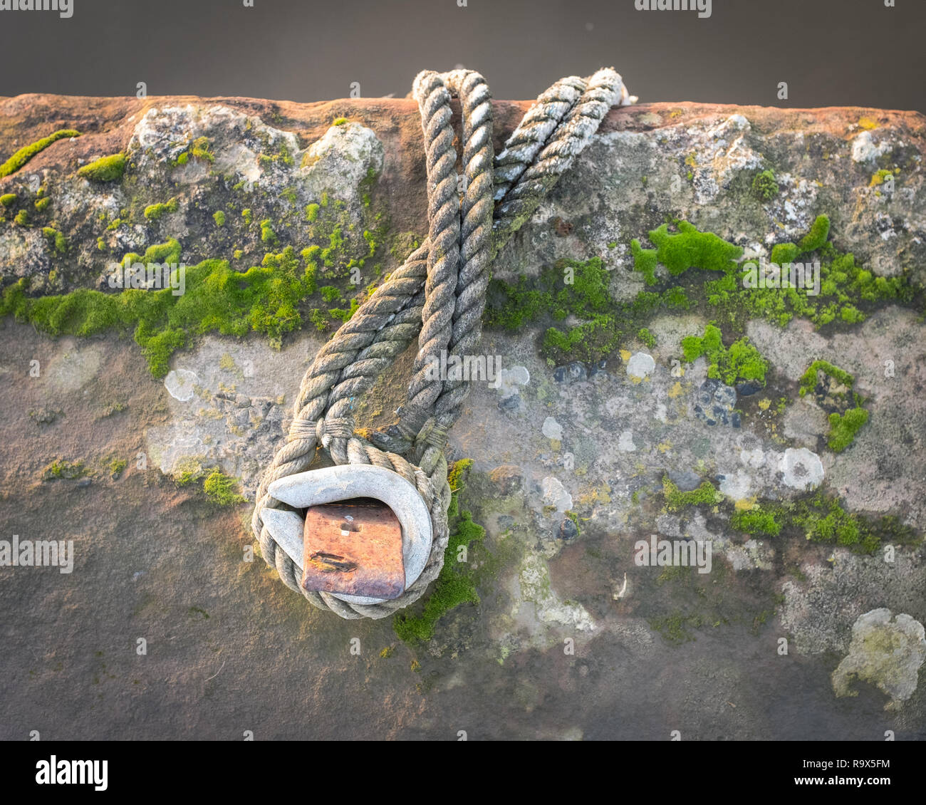 Looking down at ropes at the side of a harbour wall Stock Photo - Alamy