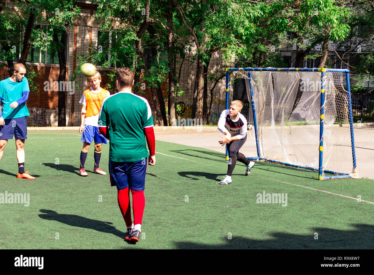 Young people play football on the green grass Stock Photo - Alamy
