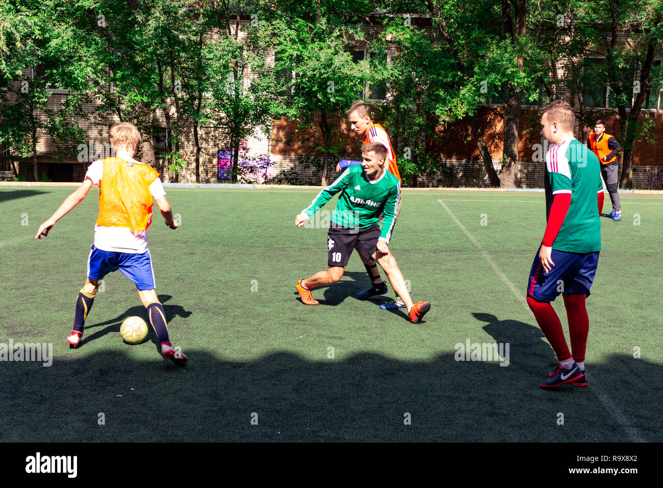 Young people play football on the green grass Stock Photo - Alamy