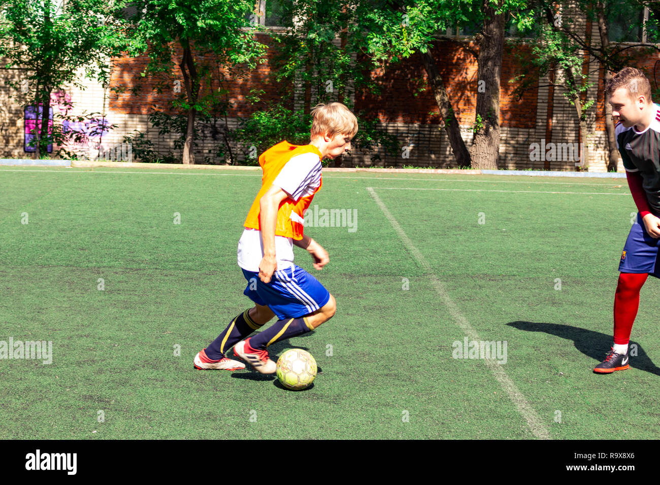 Young people play football on the green grass Stock Photo - Alamy