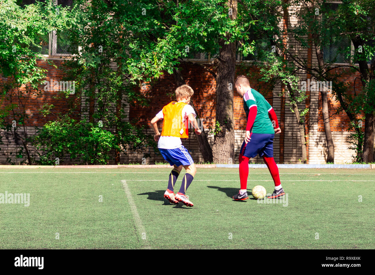 Young people play football on the green grass Stock Photo - Alamy