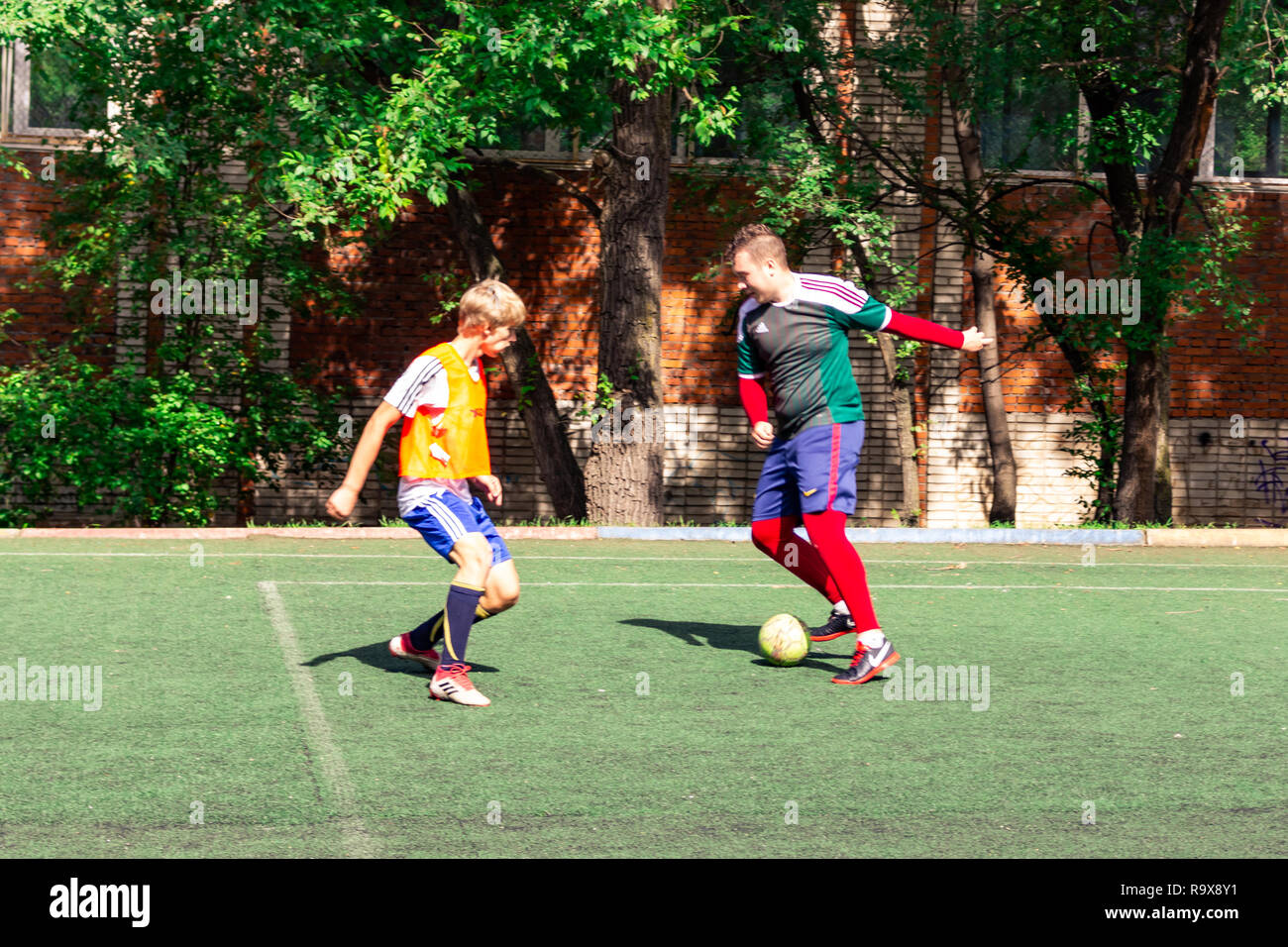 Young people play football on the green grass Stock Photo - Alamy