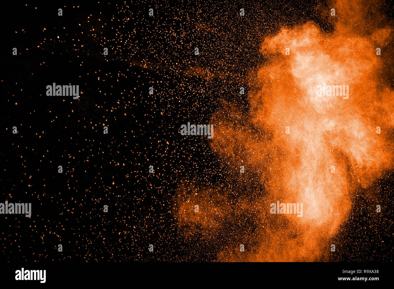 orange color powder explosion cloud on black background Stock Photo - Alamy