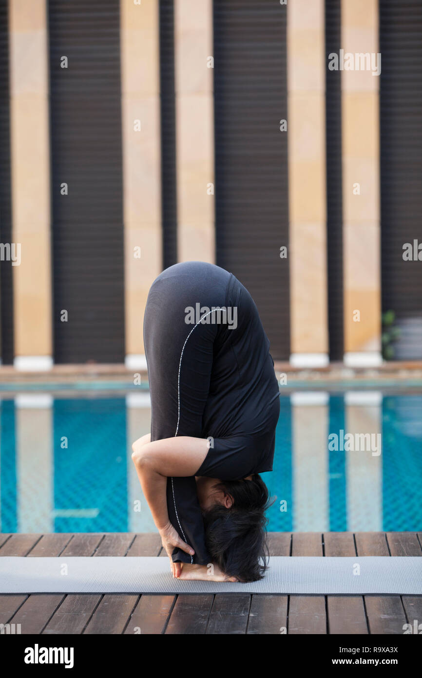 woman practicing yoga, doing head to knees, uttanasana exercise ...
