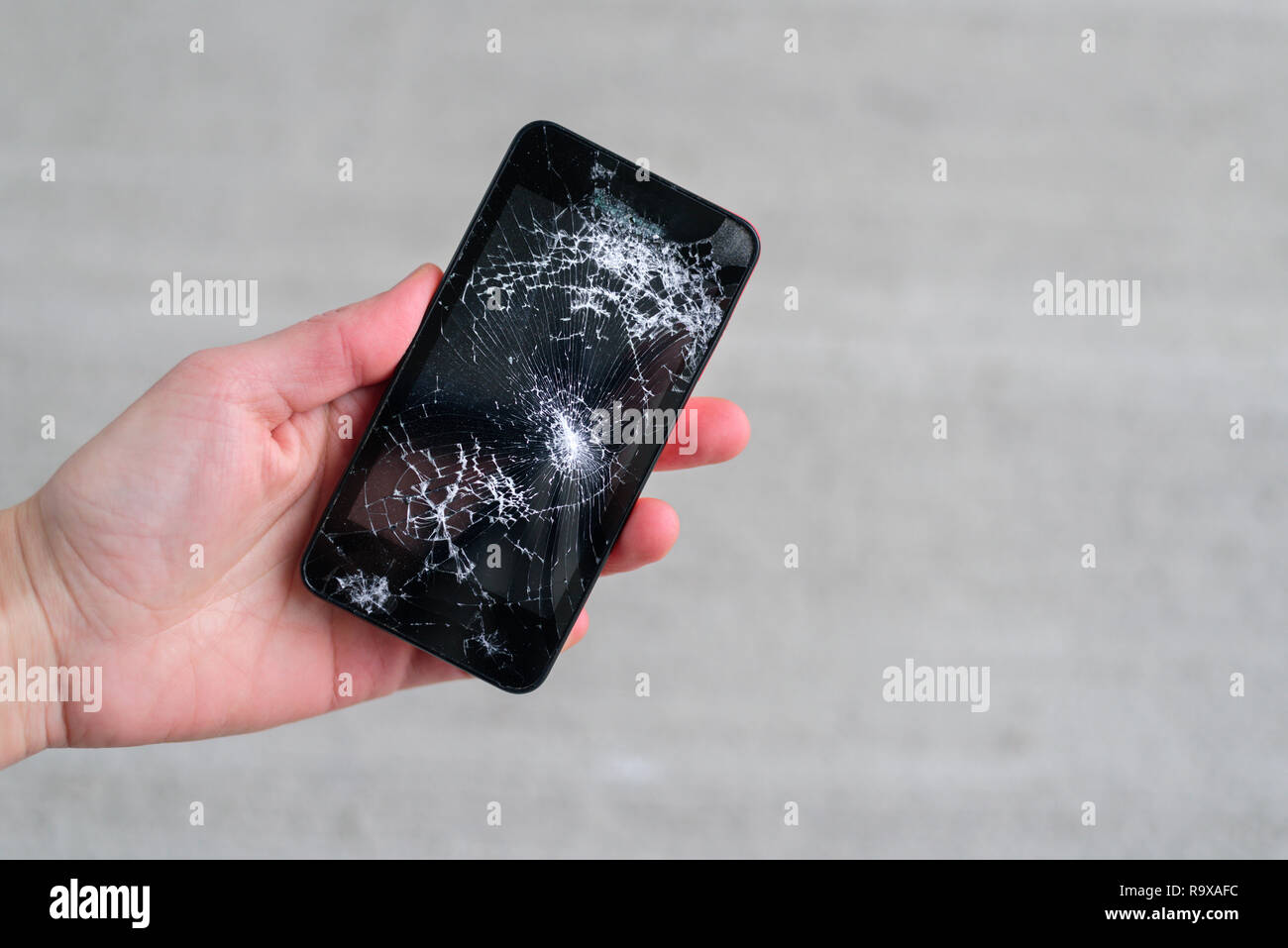 Hand holding phone with broken screen by hammer Stock Photo - Alamy