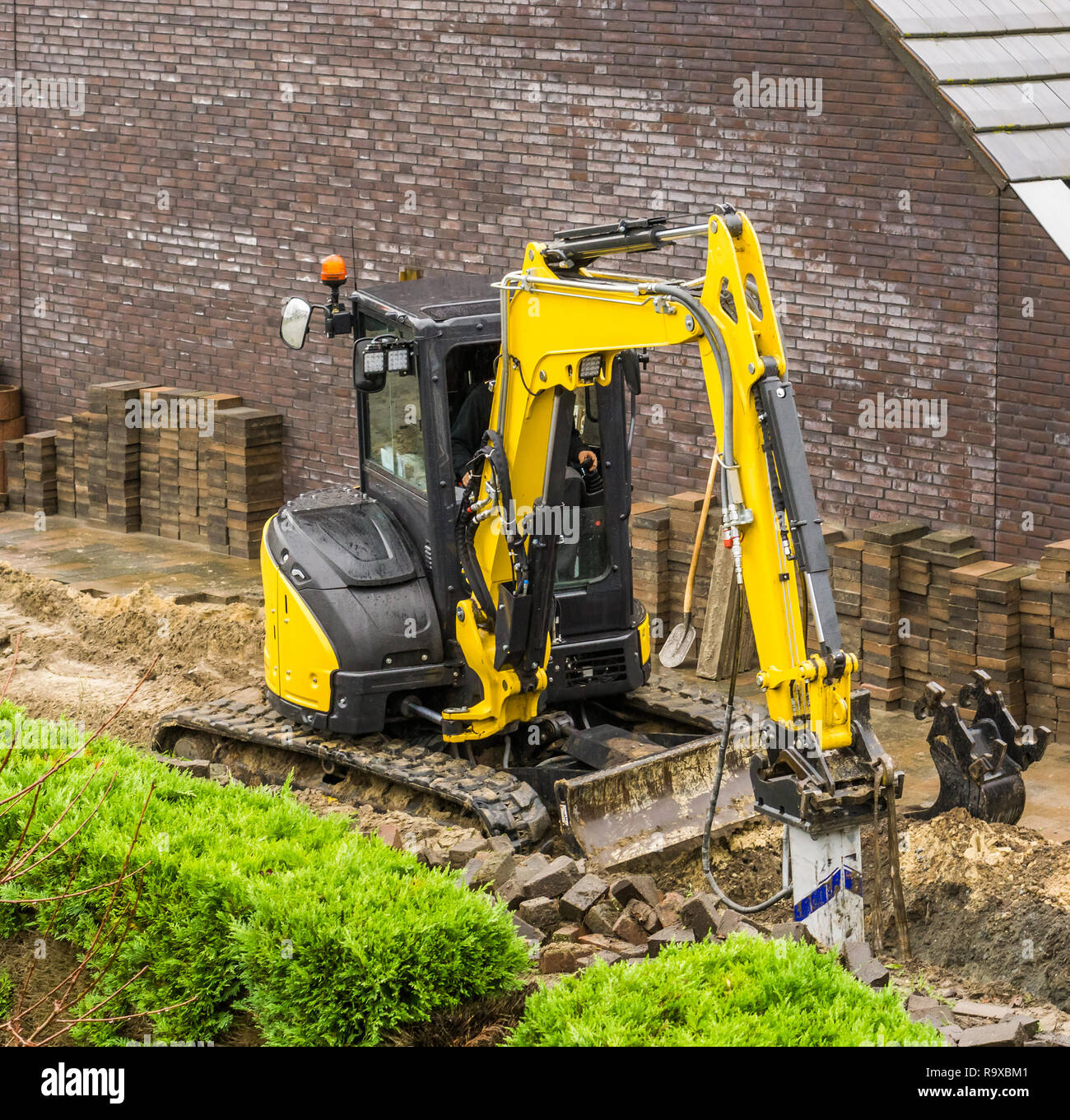 digger machine equipped with a drill working on constructing a garden ...