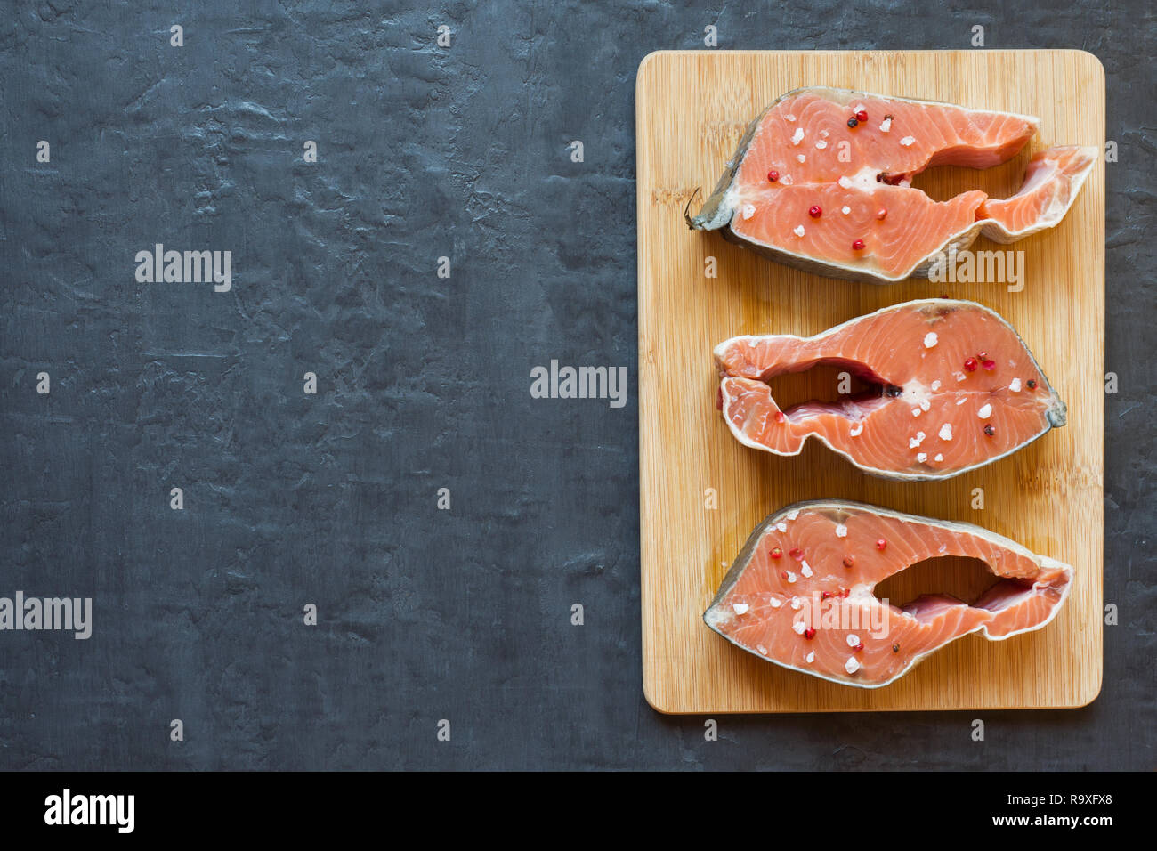 Steak raw red fish with lemon and spices dark background with copy ...