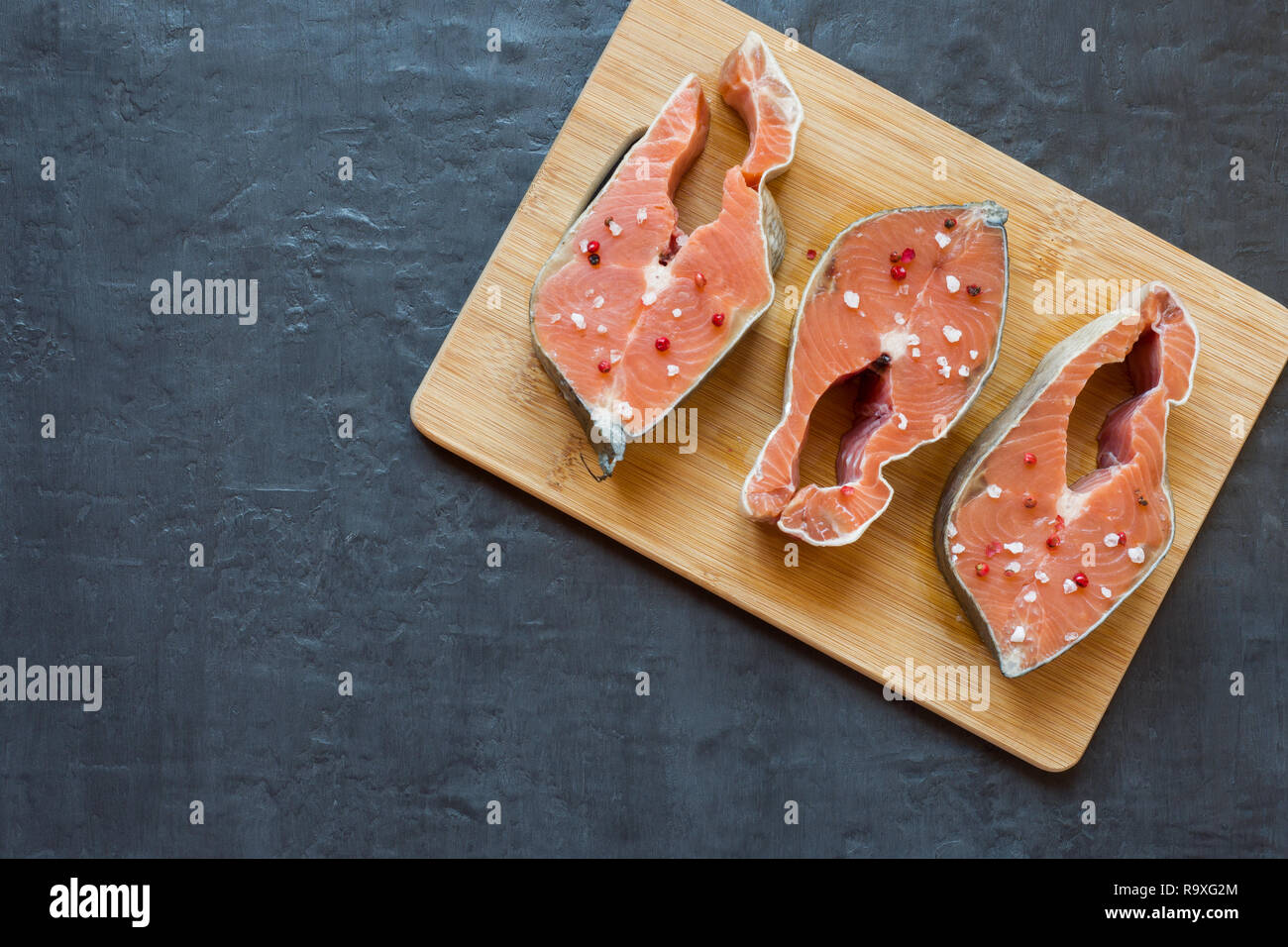 Steak raw red fish with lemon and spices dark background with copy ...