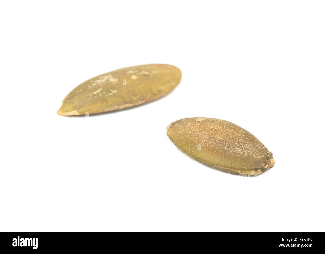 Two pumpkin seeds without shell on white background Stock Photo - Alamy