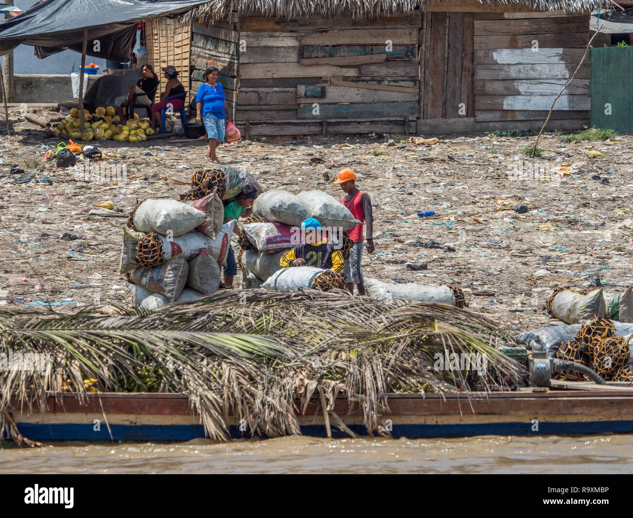Iquitos, Peru - Sep 25, 2018: Men are carring the bags with charcoal. A ...