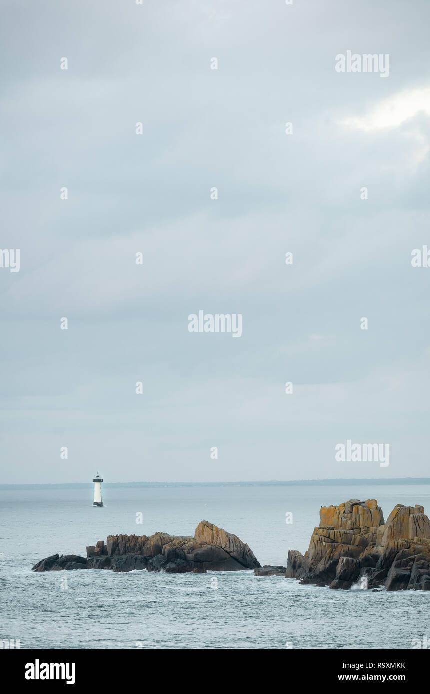 Cliffs with lighthouse in the distance, with rocks illuminated by sun ...