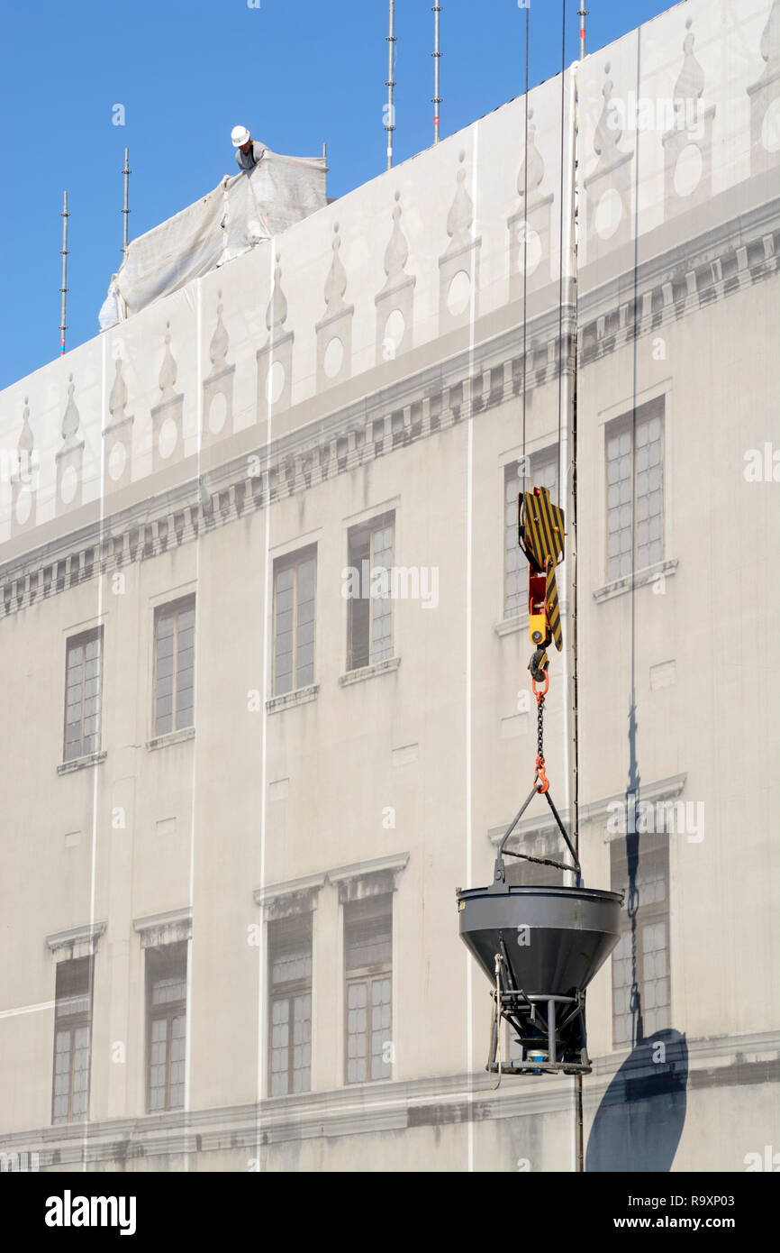 Construction site, building draped for renovation, concrete is being ...