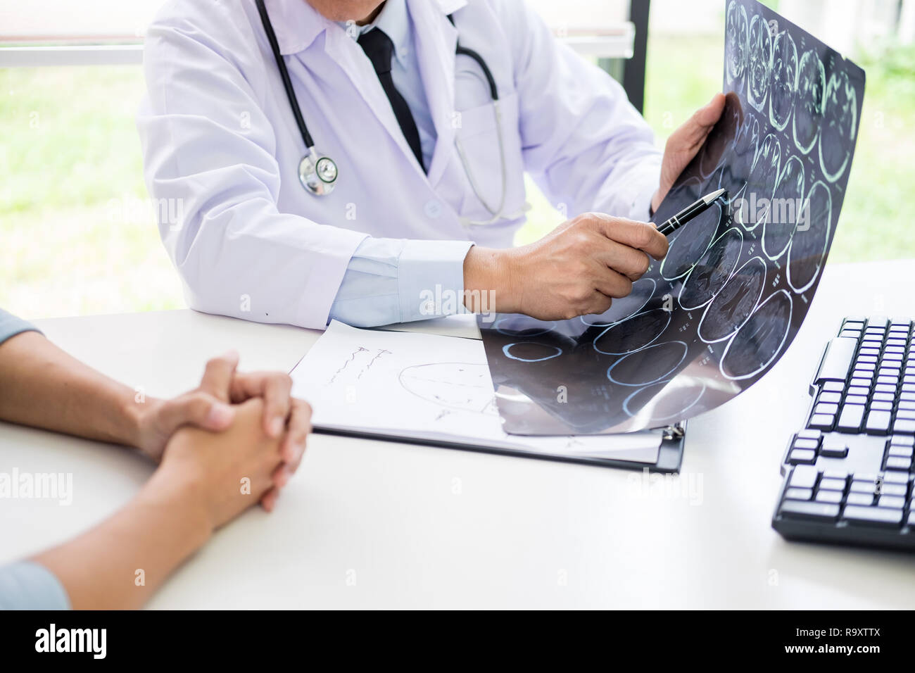 doctor analyzing a scan or x-ray film or explains a CT scan thoughtful ...