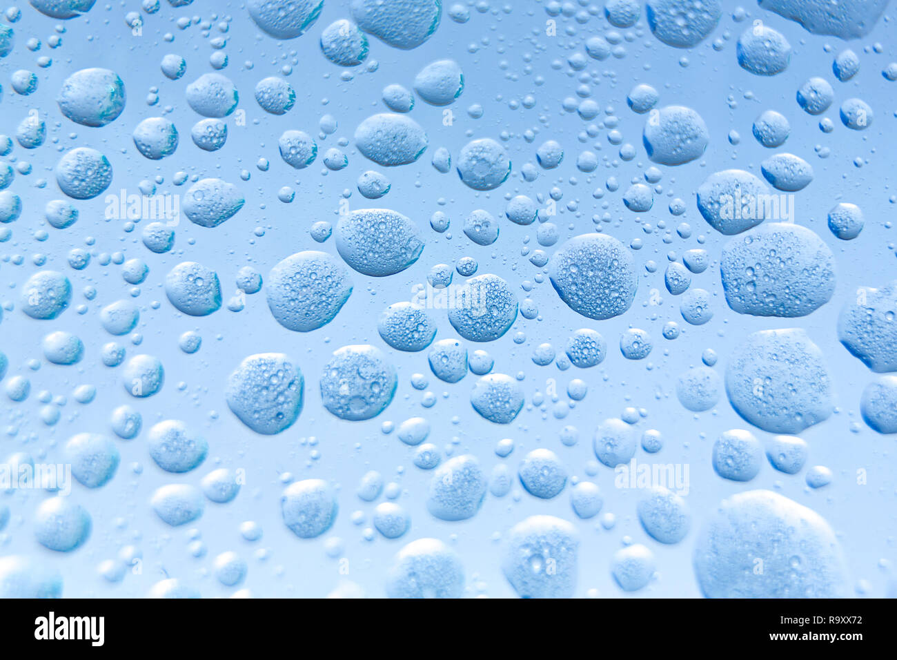Oil mixed in water on a grey and blue background. Photographed in close ...
