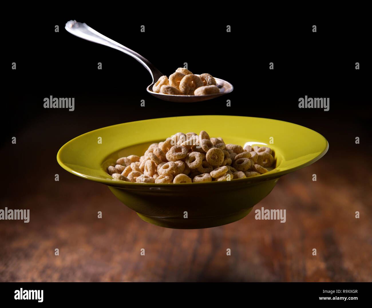 Bowl of oat cereal rings floating in the air traditional American ...