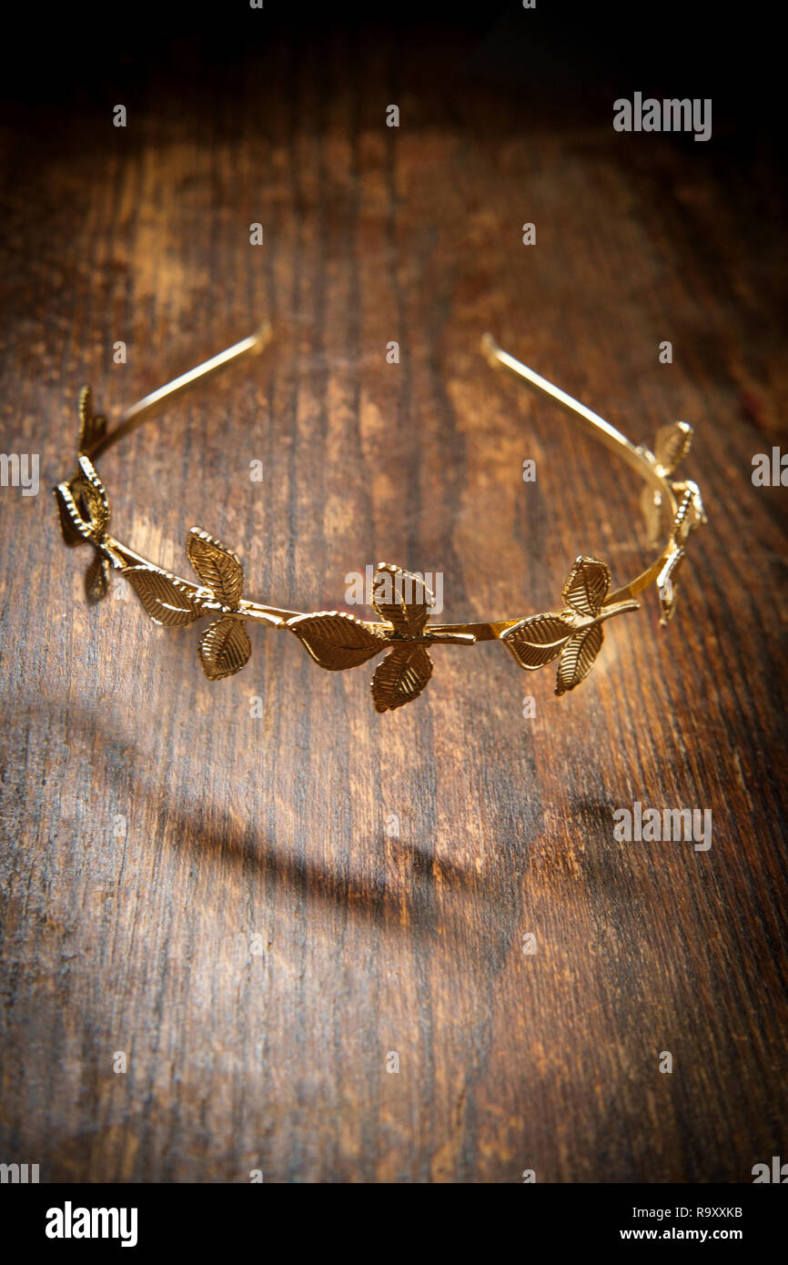 Golden laurel leaf Greek or Roman crown on dark moody wooden table ...